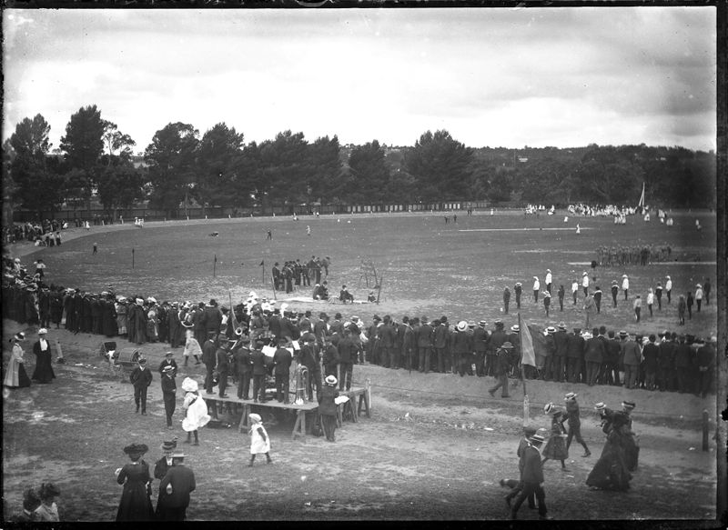 Crowd gathered at oval, band on platform in foreground - AGSA Collection