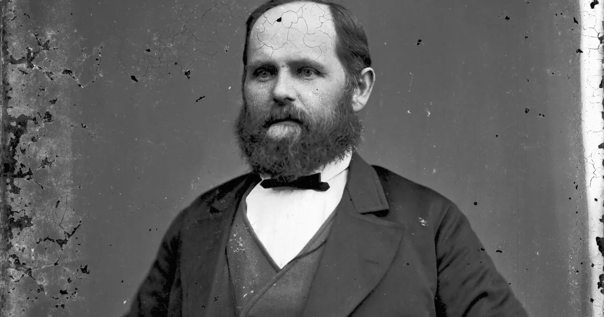 Portrait of bearded man wearing ribbon tie, hand placed on thighs ...