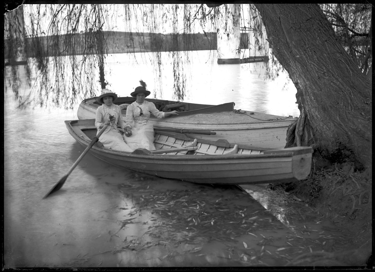 Two women in boat moored under willow tree - AGSA Collection