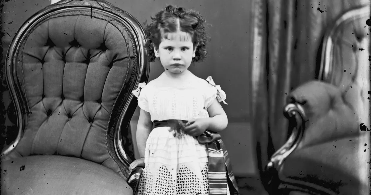 Studio portrait of small child, patterned sash at waist - AGSA Collection